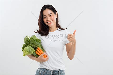 엄지 손가락으로 야채를 들고 흰색 티셔츠를 입고있는 여자