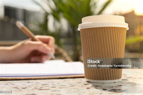 알아볼 수없는 젊은 여성은 해변 리조트에서 공부합니다 종이컵에서 커피를 마시는 것 숙제를 만드는 학생 노트북에 쓰는 여성 손 감사 저널 자기 반성 공동 작업 공간에서 자기