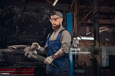 유니폼 및 안전 유리는 각 분쇄기 수리 차고에서 깨진된 자동차에 대 한 서 있는 동안 작업에 잔인 한 자동차 정비공 기계공에 대한 스톡 사진 및 기타 이미지 Istock