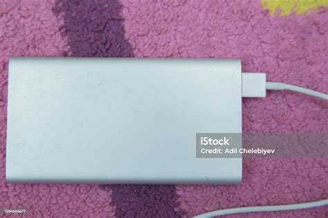 에너지 은행 나선형 Usb 케이블을 통해 실버 파워 뱅크와 스마트 폰 충전 분홍색 카펫에 전원 뱅크로 충전하는 스마트 폰 Usb 케이블에 대한 스톡 사진 및 기타 이미지