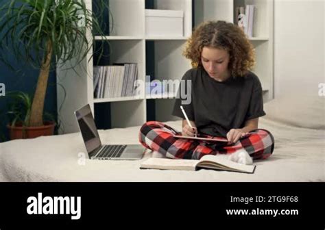 Cute Teenage Girl Doing Homework Sitting On The Bed At Home A Young Beautiful Girl Thinks And
