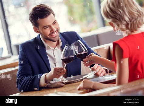 Young Man And Woman On Date In Restaurant Sitting Table Holding Glasses