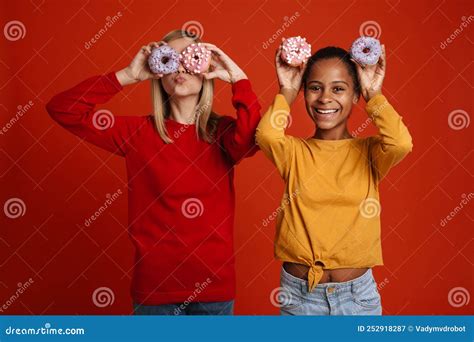 Multiracial Two Girls Laughing While Making Fun With Donuts Stock Image