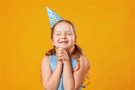 귀여운 어린 소녀는 생일을 맞는다 아이는 그의 눈을 감고 소원을 했다 노란색 배경에 근접 촬영 초상화입니다 파티에 대한 스톡