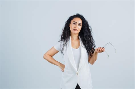 흰색 티셔츠 재킷을 입은 안경을 들고 자신감을 보이는 젊은 여성 전면보기 무료 사진