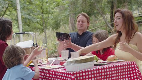 Vídeo Gratis Feliz familia caucásica haciendo un picnic en el bosque comiendo y pasando