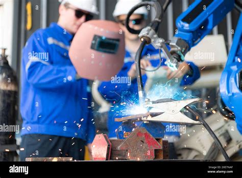 Industrial Workers Working With Robotic Arm Welding Machine In Factory Robotic Arm Welding