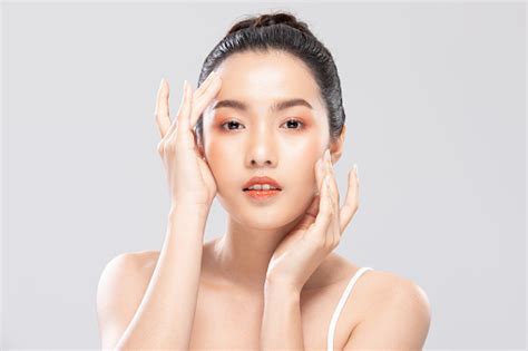 깨끗하고 신선한 피부로 부드러운 뺨 미소를 만지는 아름다운 아시아 젊은 여성 행복과 흰색 배경에 고립 된 긍정적 인 감정으로 쾌활합니다 뷰티와 화장품 컨셉의 셀프케어 20