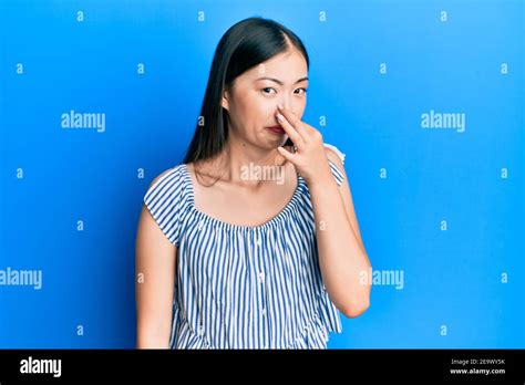 Young Chinese Woman Wearing Casual Striped T Shirt Smelling Something
