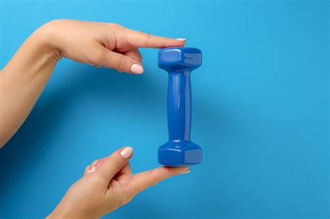 스포츠 컨셉 파란색 플라스틱 아령을 들고 있는 여성의 손 파란색 배경입니다 여자의 손 리프팅 아령 개념에 대한 스톡 사진 및