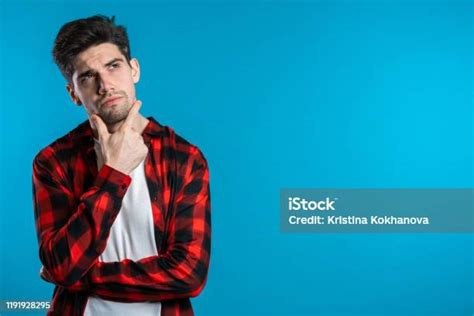 공간을 복사합니다 파란색 배경을 위를 올려다 보는 남자를 생각 걱정스러운 표정 빨간 셔츠에 잘 생긴 남성 모델입니다 긍정적인 감정 표현에 대한 스톡 사진 및 기타 이미지