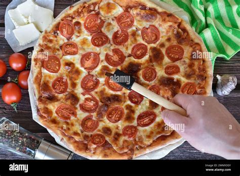 Hand Holding Pizza Cutter Fresh Baked Pizza Margherita On Rustic