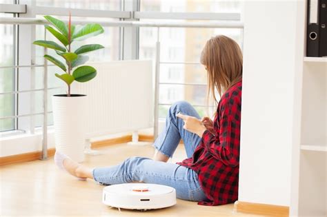 Premium Photo Woman Enjoys The Work Of A Smart Robot Vacuum Cleaner