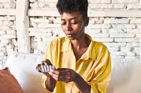 Premium Photo Seated On Her Sofa An African Woman Takes Her Pills
