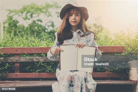 복고풍 드레스 공원에서 벤치에 앉아 젊은 아시아 여자 그녀는 당신이 노트북에서 뭔가 보여주는 빈 빈 노트북을 들고 빈티지