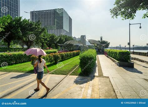 Female Tourist With Umbrella Crossing Grassed Track Guangzhou