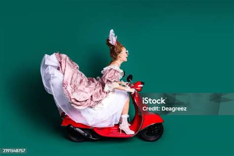 분홍색 바로크 양식의 드레스를 입은 우아한 여성이 녹색 배경에 빨간 스쿠터를 타고 과거와 현대 시대의 대조를 보여줍니다 공주에