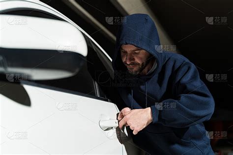 穿帽衫的小偷在晚上偷车