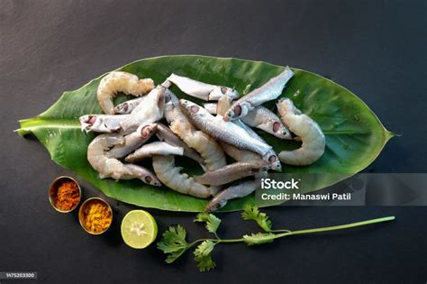 인도 흰 숭어 물고기 또는 보이 생선과 새우를 녹색 바나나 잎에 향신료와 요리 재료를 검은 뒷면에 넣고 신선한 생선 허브 및