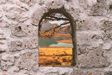 Scenic View Of A Tranquil Lake Seen Through A Stone Arch Window Stock