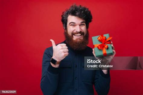 좋은 선물 휴가를 즐기는 사람 선물 상자를 들고 수염을 기고한 남자 그리고 빨간 배경 위에 엄지 손가락을 보여주는 사람 선물에 대한 스톡 사진 및 기타 이미지 Istock