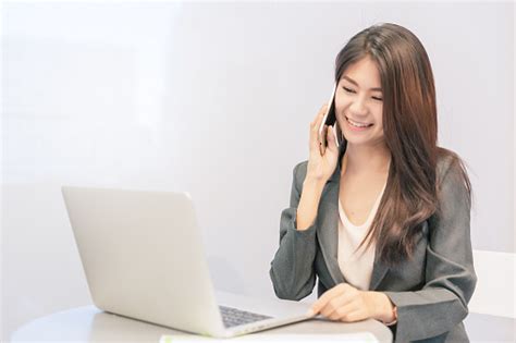 비즈니스 여자 얘기 하는 배경에 대 한 컴퓨터 노트북 현대 사무실에서 고객에 게 스마트 폰 가리키기에 대한 스톡 사진 및 기타