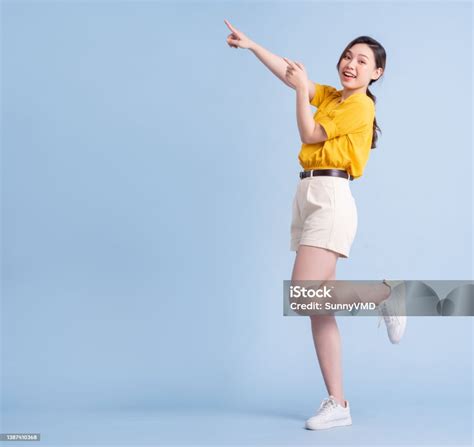푸른 배경에 포즈를 취하는 젊은 아시아 여성의 전체 길이 이미지 가리키기에 대한 스톡 사진 및 기타 이미지 가리키기 귀여운 동양인 Istock