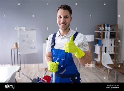Full Length Portrait Of Happy Male Worker With Broom Cleaning Office