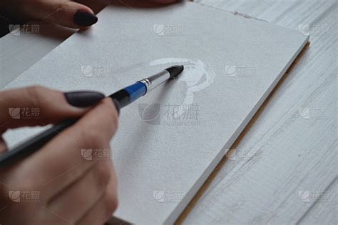 女人在素描簿上画画。白色木桌上的绘画工具。画家的工作。