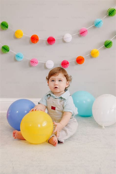 그의 첫 번째 생일을 축하하는 재미있는 백인 아기 아이 아이 유아는 화려한 풍선으로 바닥에 앉아 있습니다 집에서 실내에서