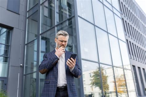 Um Homem Mais Velho De Cabelos Grisalhos De Terno E óculos Fica Do Lado