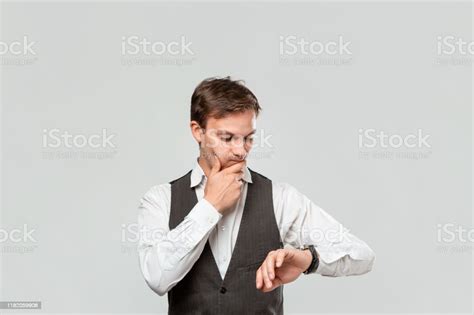 흰색 셔츠와 회색 조끼를 입은 젊은 사업가가 손목 시계에 시간을 확인합니다 시간 엄수의 개념 시계에 대한 스톡 사진 및 기타