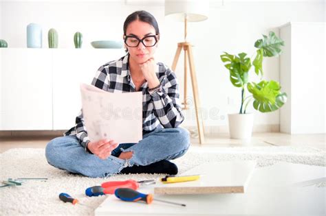Woman Who Is Assembling Furniture In Her Home As Part Of A Renovation