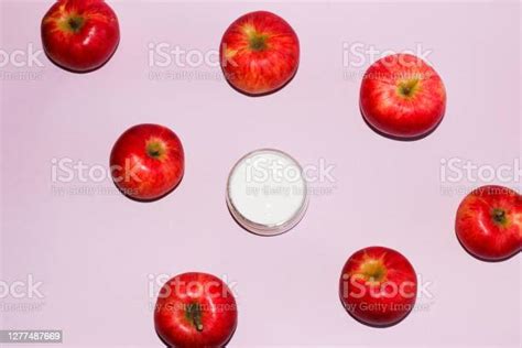 붉은 잘 익은 육즙이 많은 사과와 분홍색 배경에 흰색 부드러운 보습 크림오픈 항아리와 화장품 구성 건강한 식생활에 대한 스톡