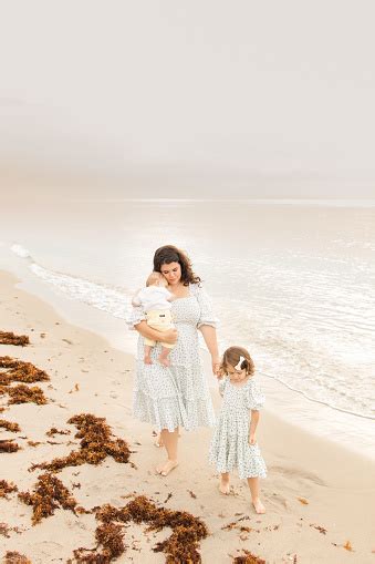 30 세의 쿠바 어머니 쿠바 계 미국인 3 살짜리 딸과 6 개월 된 아들과 손을 잡고 2022 년 6 월 플로리다 팜 비치의 모래 사장을 걷고있는 동안 팔에 말려 들었다