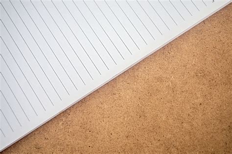 나무 표면에 줄이 그어진 공책 페이지를 닫습니다 글쓰기 일기 쓰기 또는 메모 작성에 적합합니다 깔끔한 선과 단순한 배경은 교육 또는 사무 관련 테마에 이상적입니다 0명에