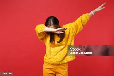 스튜디오에서 밝은 빨간색 배경에 고립 된 Dab 댄스 제스처를 보여주는 하강 머리와 노란 모피 스웨터에 젊은 여자의 초상화 사람들은 진심으로 감정 라이프 스타일 개념입니다