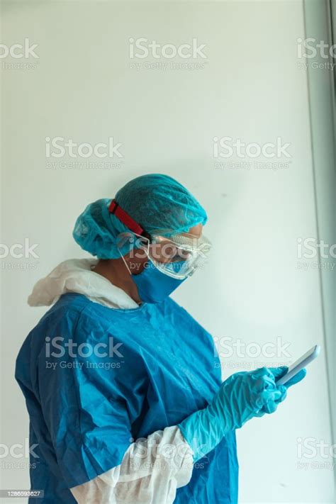 파란 유니폼을 입은 젊고 진지한 의사와 병원에서 휴대 전화와 라텍스 장갑을 착용하고 일하는 의료 용 마스크 건강관리와 의술에