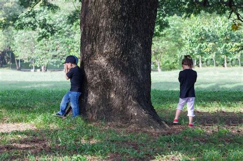 Premium Photo Siblings Playing Hide And Seek At Park