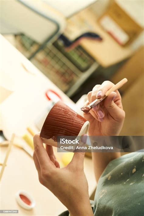 유약으로 점토 머그잔을 그리는 소녀의 클로즈업 페인트 브러시로 작업장에서 도자기를 색칠하는 여성 녹색 앞치마 글레이징 점토 냄비에 화가 공예에 대한 스톡 사진 및 기타