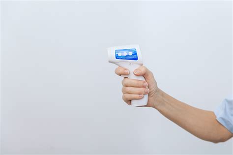 의사의 손에 온도 측정 총 적외선 등자극 온도계 총을 사용하여 바이러스 증상에 대한 체온을 확인할 준비가 된 보호 수술 용