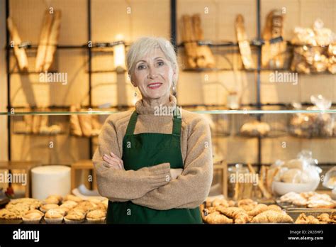 Cheerful Mature Female Baker Welcoming Everyone Into Her Bakery Stock