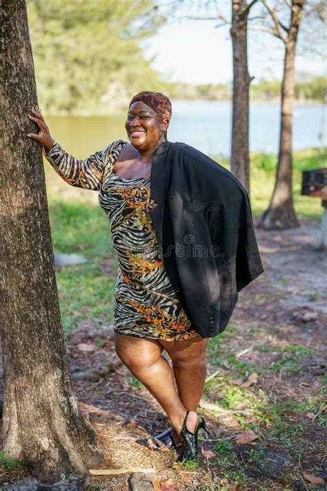 Beautiful Black Plus Sized Model Posing By A Tree In A Tranquil Park