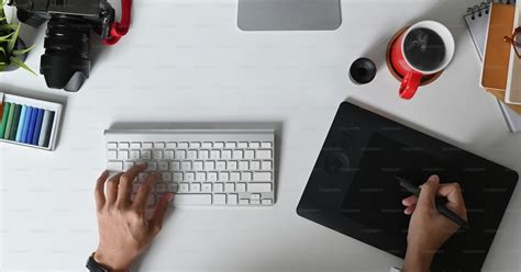 그래픽 디자이너가 키보드에 입력하고 그래픽 태블릿에서 작업하는 상위 뷰입니다 사진 Unsplash의 보고 이미지