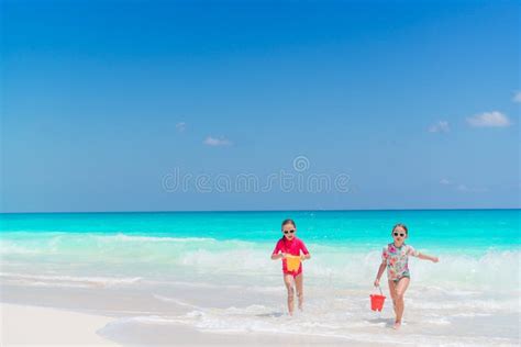 Two Little Happy Girls Have A Lot Of Fun At Tropical Beach Playing