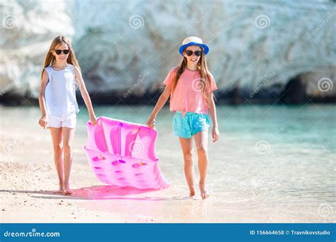 Two Little Happy Girls Have A Lot Of Fun At Tropical Beach Playing