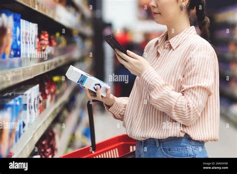 Close Up Of Caucasian Woman Scan Qr Code Of Product Using Smartphone Shelves With Food In