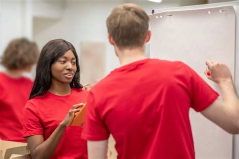 Волонтерское движение молодые добровольцы темнокожая девушка и кавказский парень стоя спиной