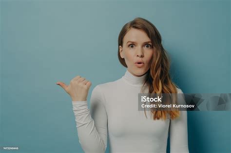 Excited Millennial Lady Standing With Thumb Finger Pointing Aside On