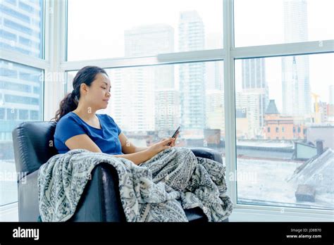 Woman Sitting In Chair By Window Day Using Mobile Phone Asian Long